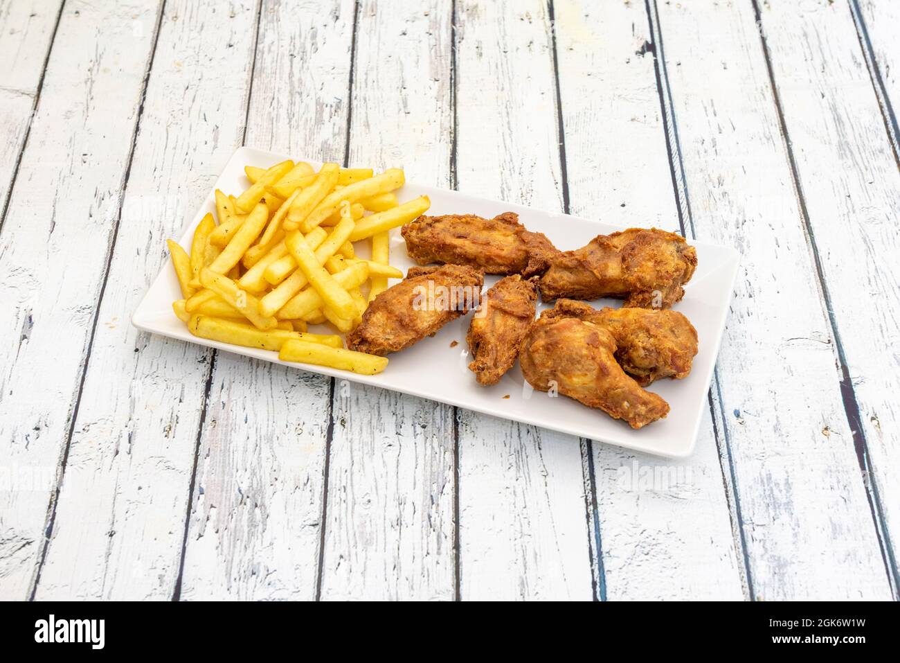 tray of fried wings battered in flour garnished with French fries on a ...