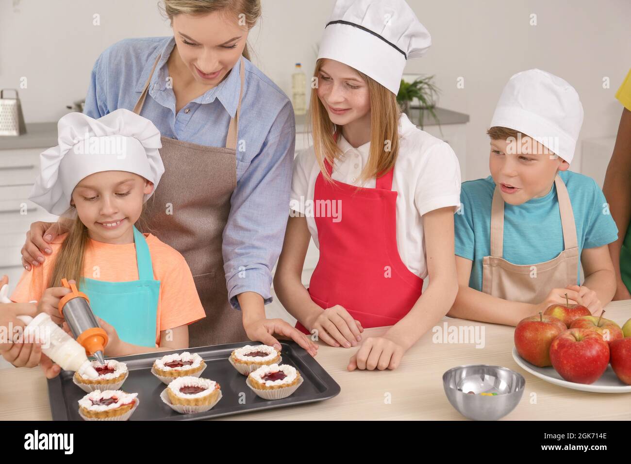 Group of children and teacher preparing dessert during cooking classes ...