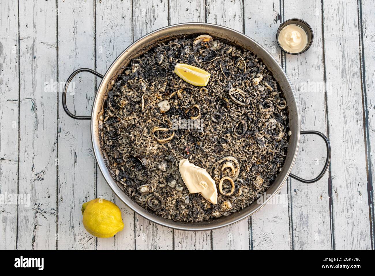 Spanish paella of black rice with squid, fish and clams with aioli ...