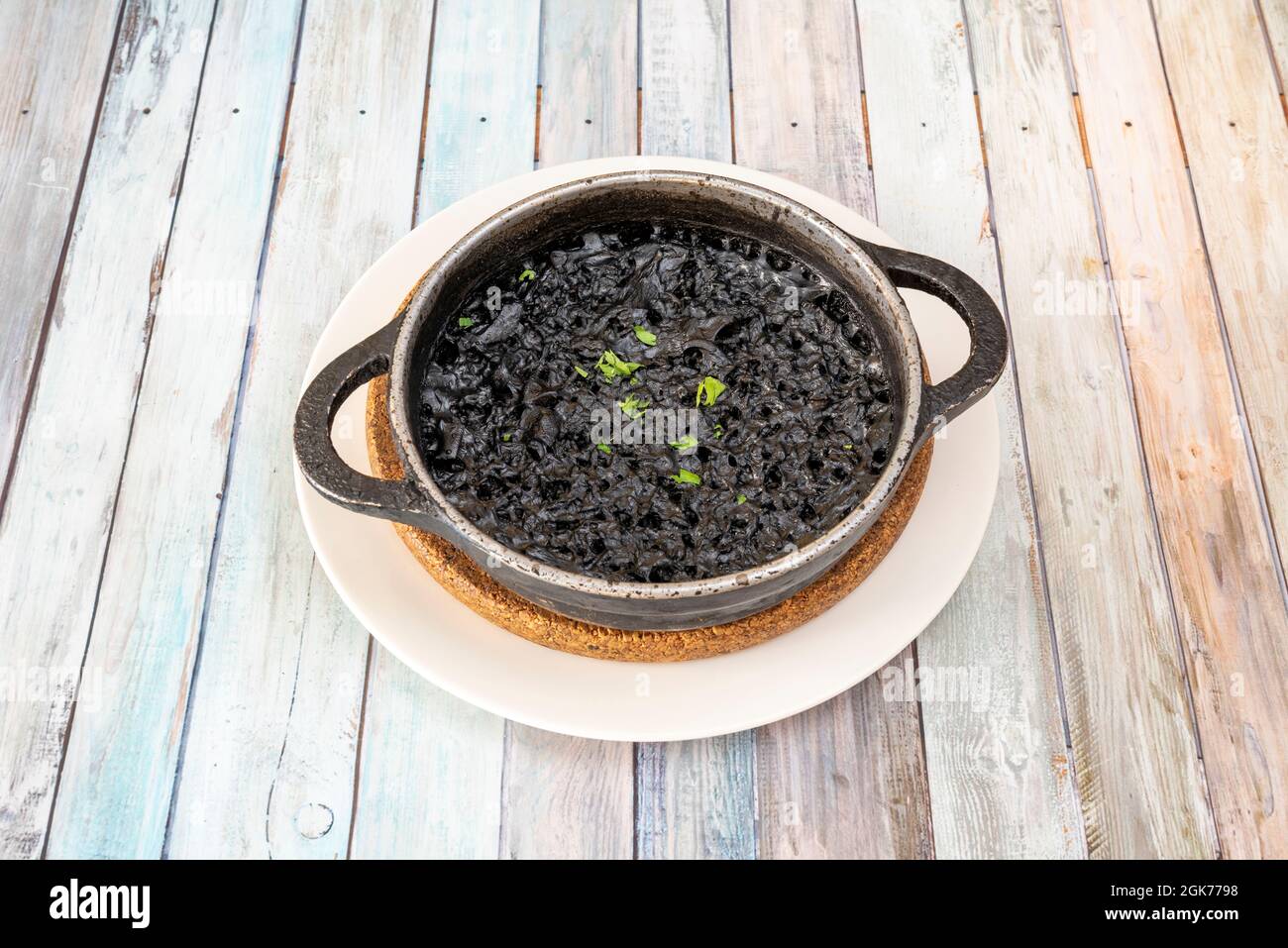 metal casserole containing a portion of black seafood paella to serve ...
