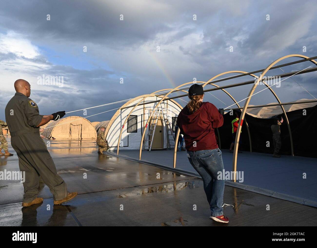 Airmen pull the tarp roof over the skeletal structure of a pod during ...