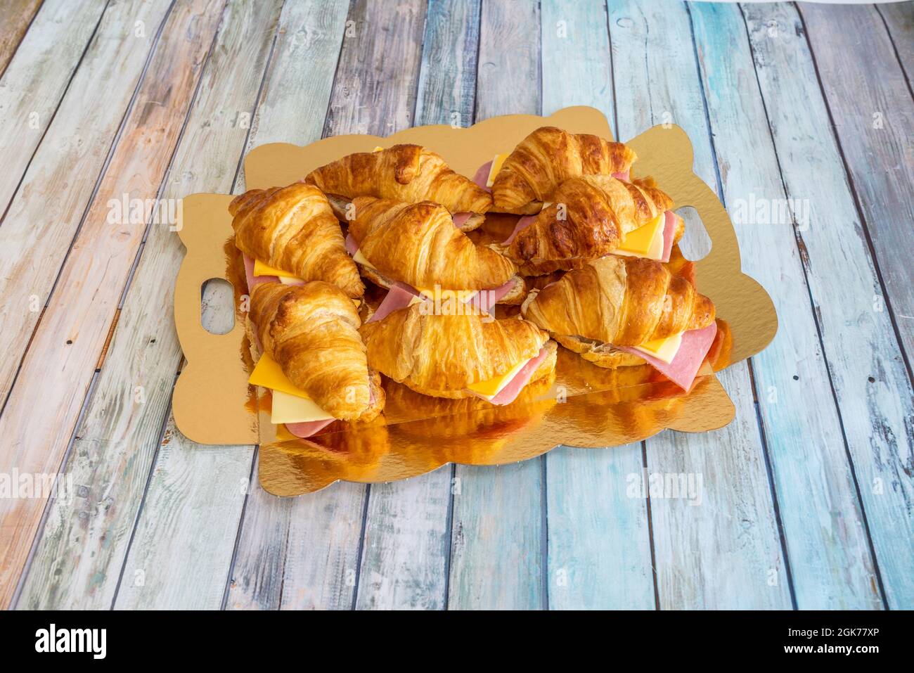 golden cardboard tray with mixed croissants with ham and sandwich ...