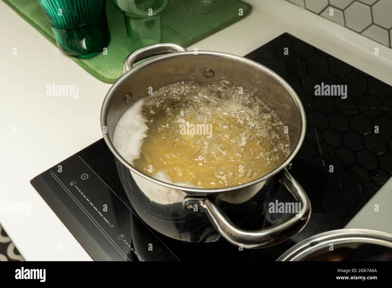Stainless steel pot filled with boiling water on black ceramic hob ...