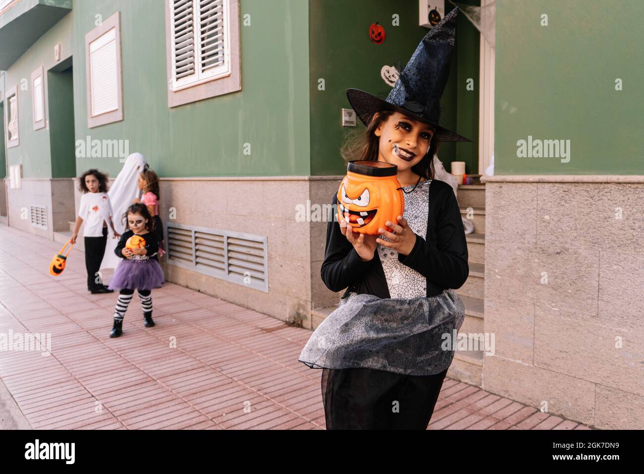 Portrait of a girl in disguise with a pumpkin and her friends in the ...