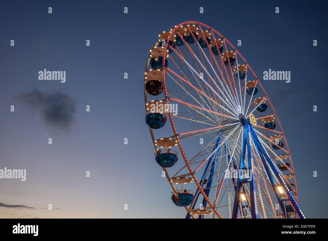 Low angle view of spinning white giant ferris wheel with blue ...