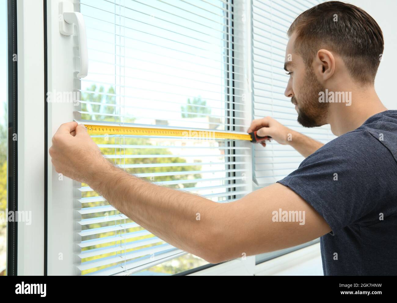Young man installing window shades at home Stock Photo - Alamy