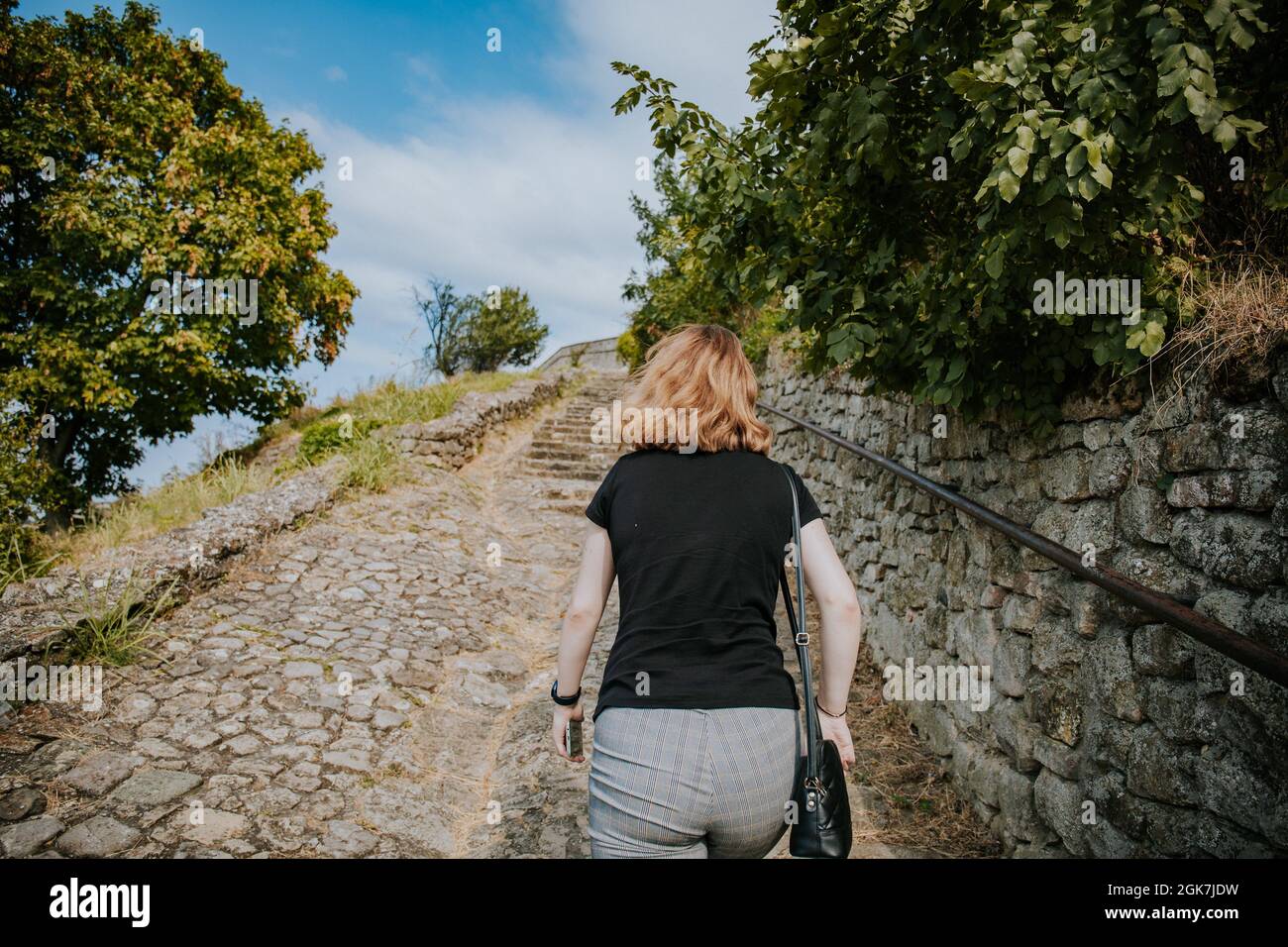 Back view of a young brunette stylish adventurous female climbing up a ...