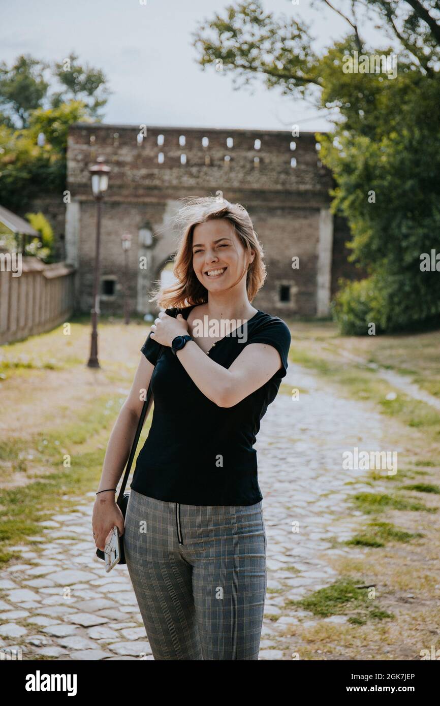 Vertical of a cheerful beautiful Bosnian female posing on the pathway ...