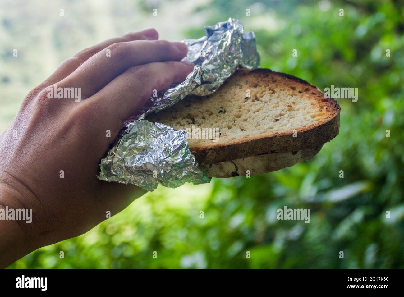 Human hand holding a bread in aluminium foil Stock Photo - Alamy