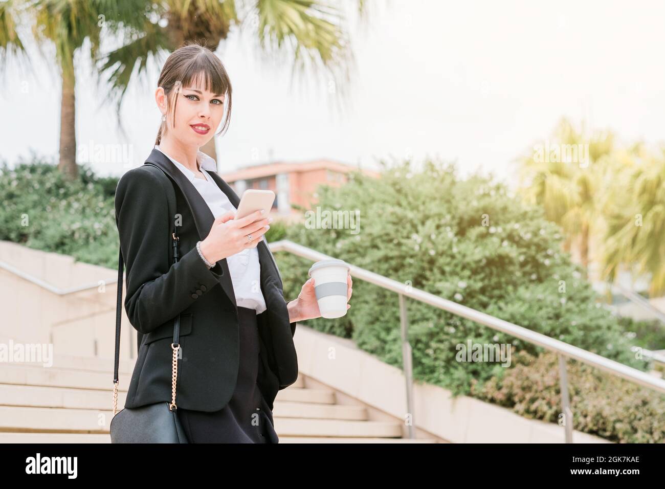 Portrait of beautiful business woman using smartphone on her way to ...