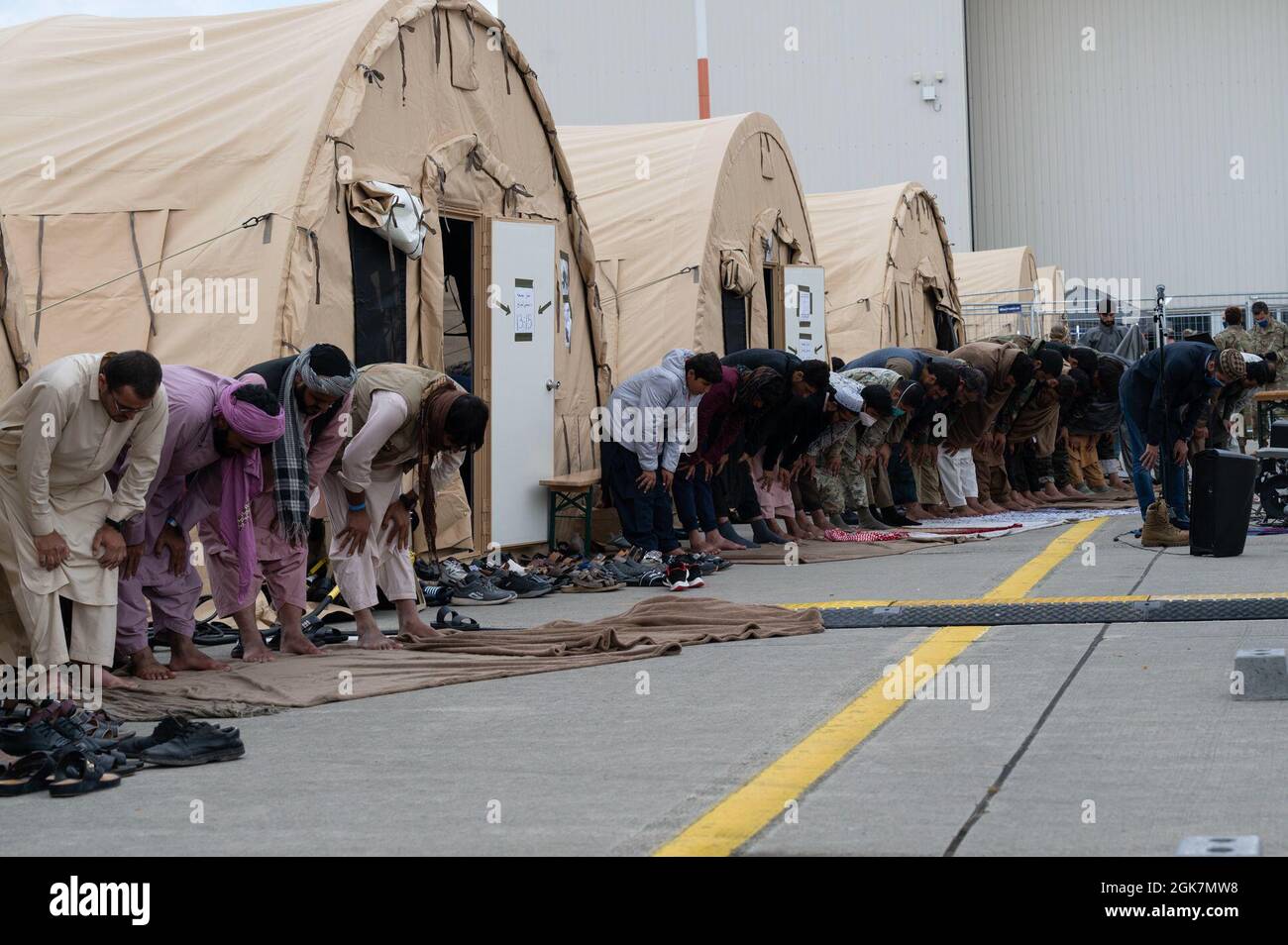 Evacuees bow during an Islamic ritual during Operation Allies Refuge ...