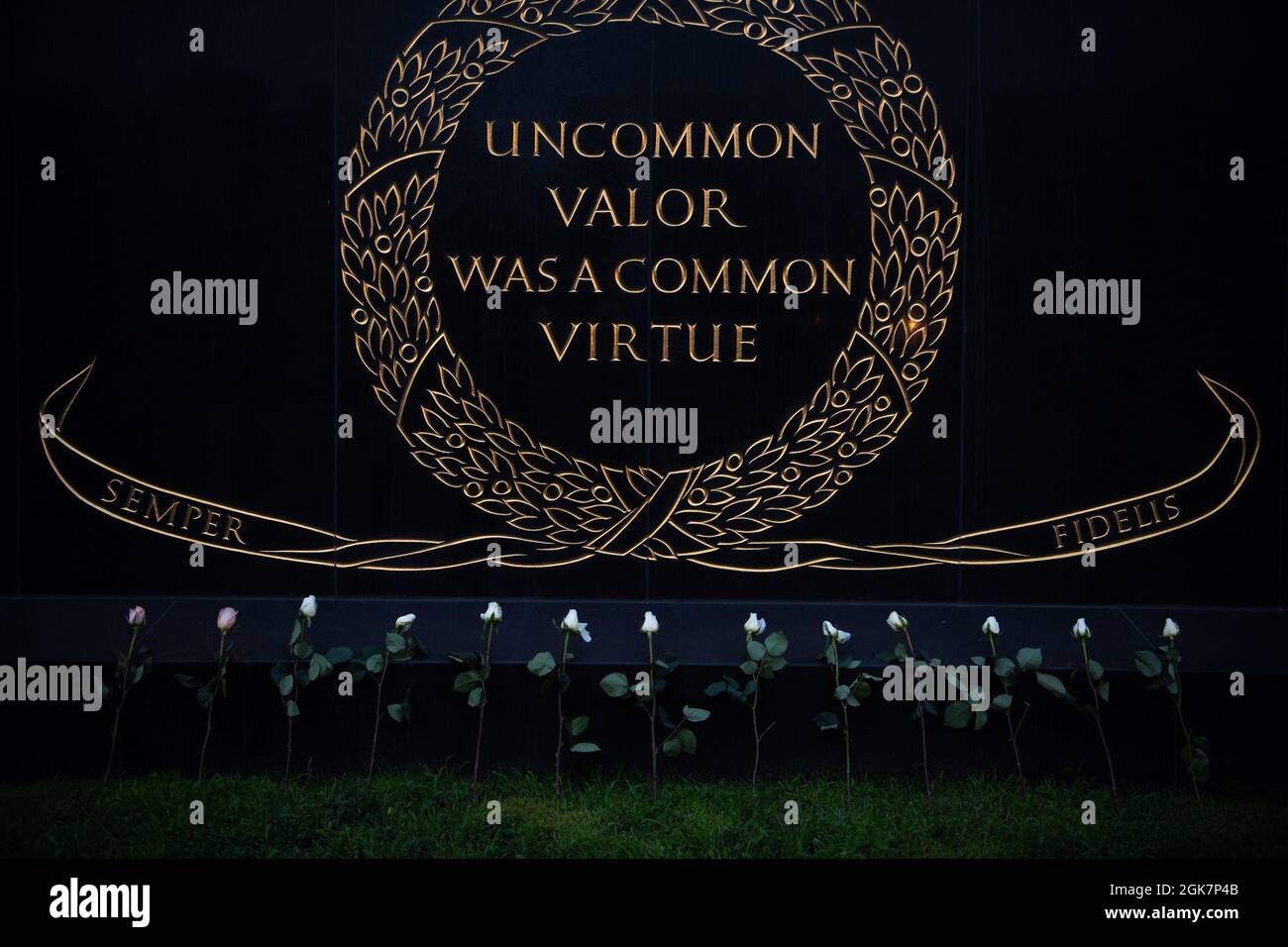 Thirteen roses, two pink and eleven white, rest on the pedestal of the ...