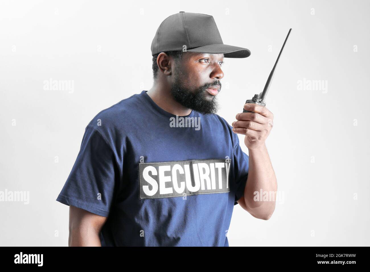 Male security guard using portable radio on light background Stock ...