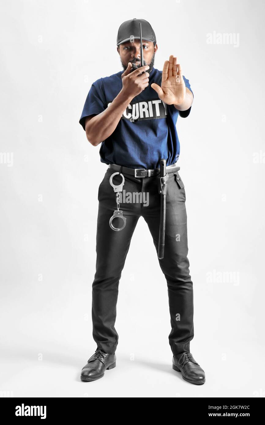 Male security guard showing stop gesture while using portable radio, on ...