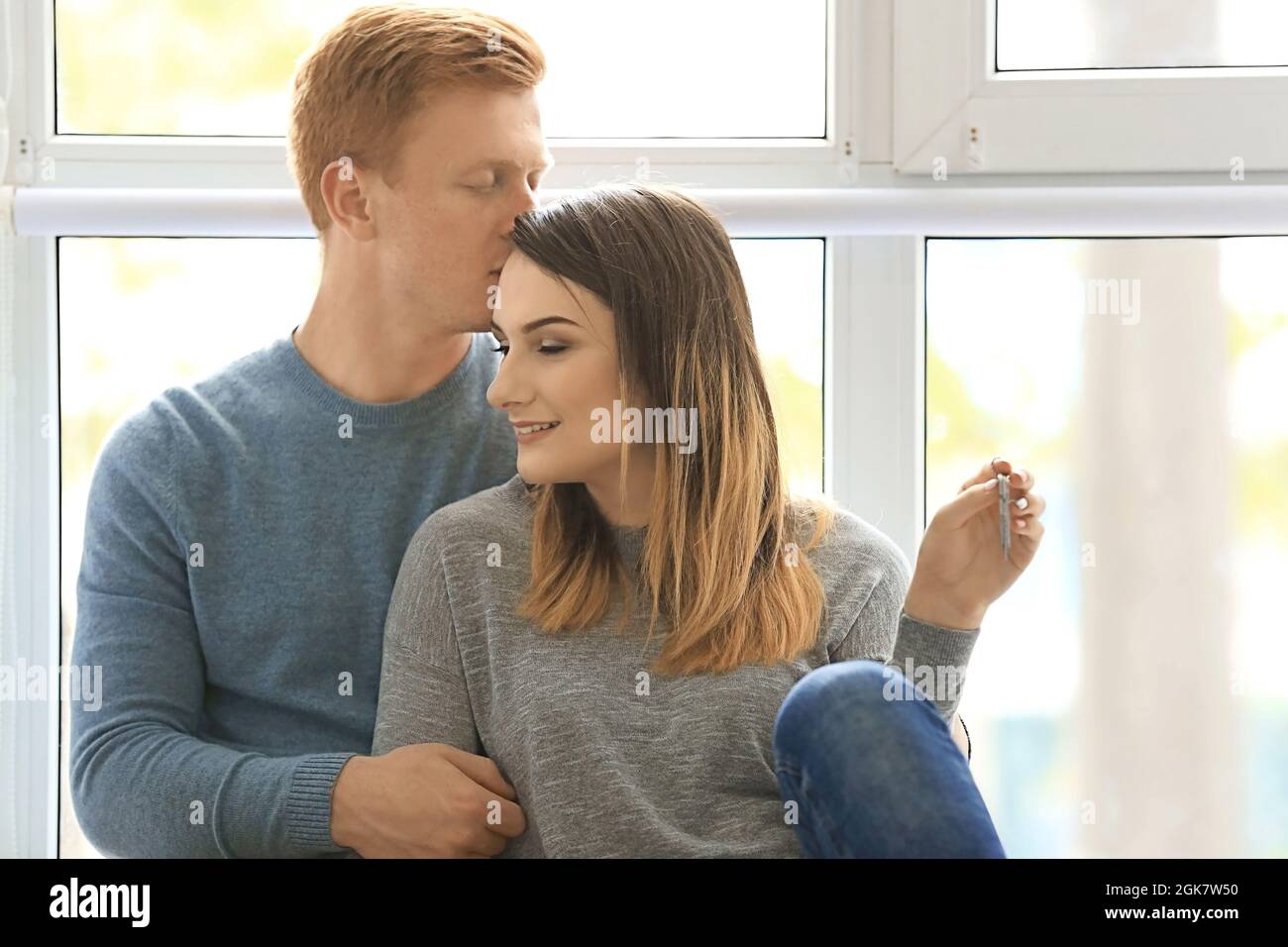 Lovely couple sitting near window with keys from new flat Stock Photo ...