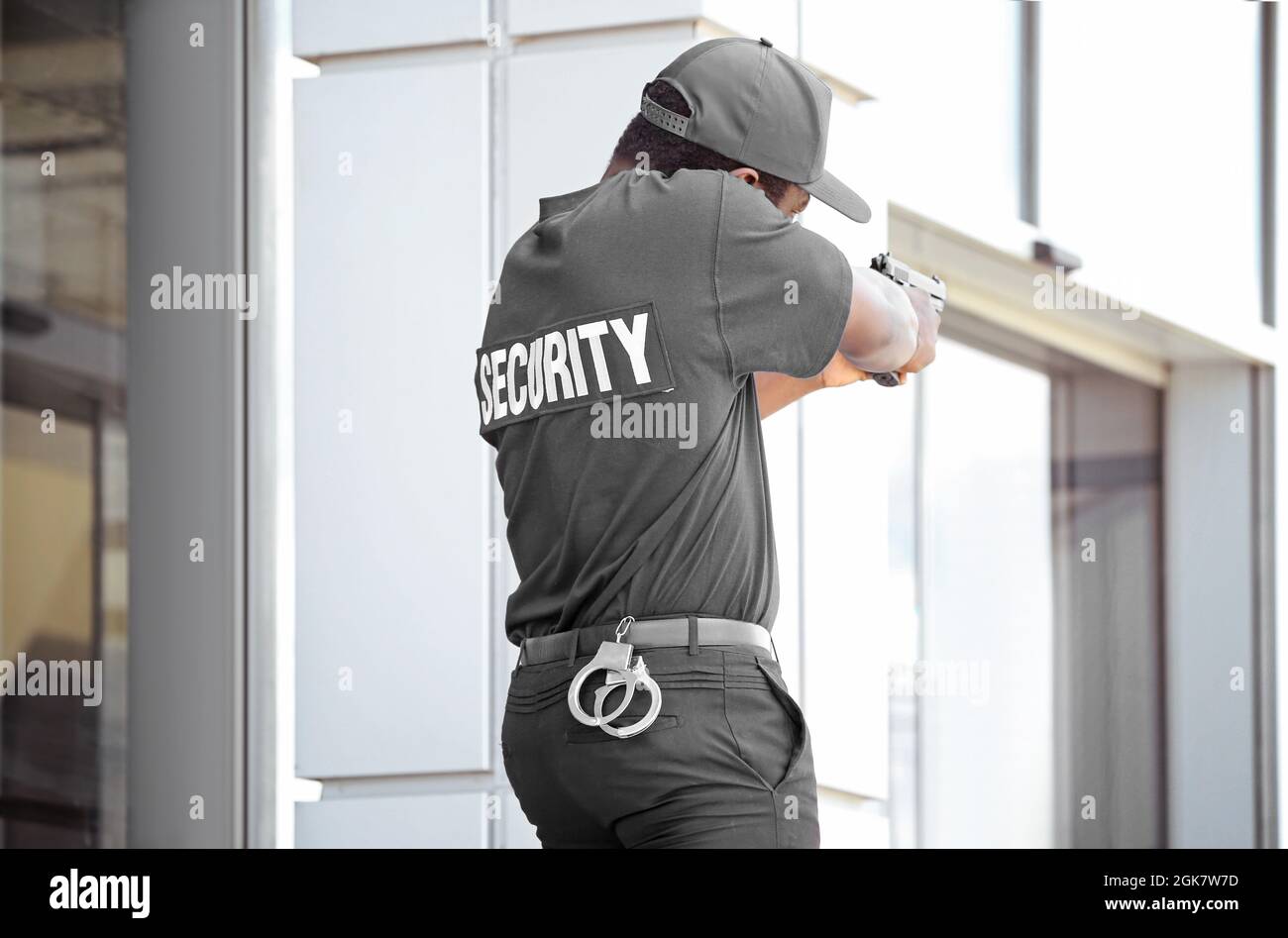 Male security guard taking aim near big modern building Stock Photo - Alamy