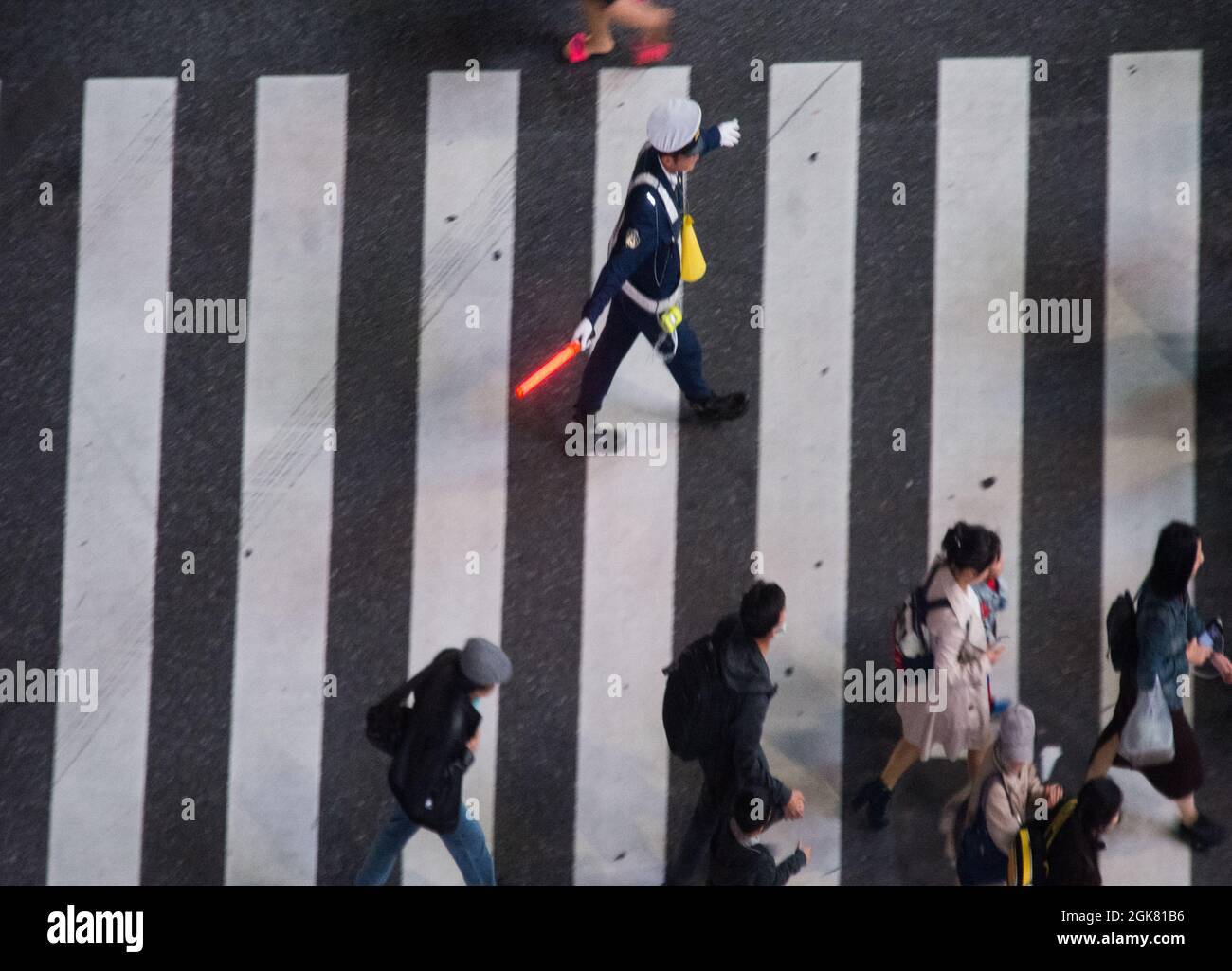 Japanese policeman with a glowstick, herding people along at the ...
