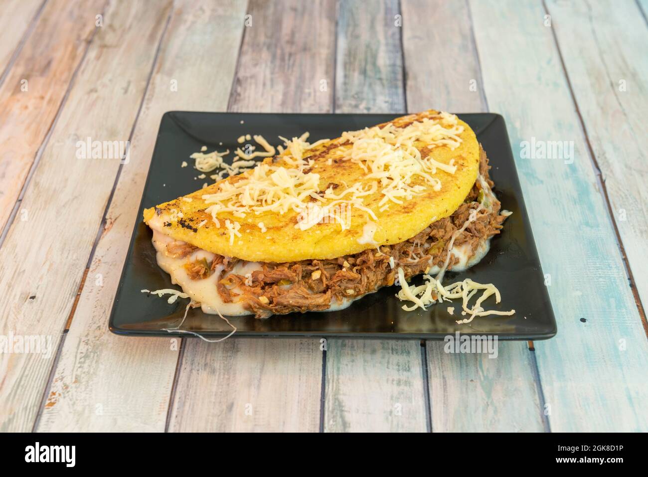 Corn cachapa filled with melted fresh cheese and a ball of butter on ...