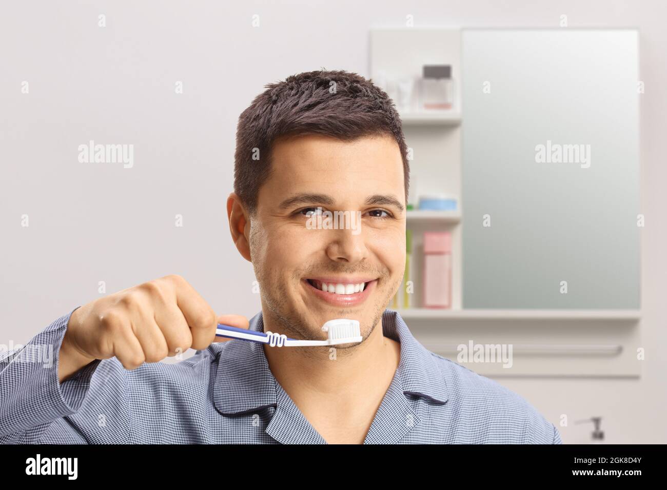 Young man holding a toothbrush with toothpaste inside a bathroom Stock ...