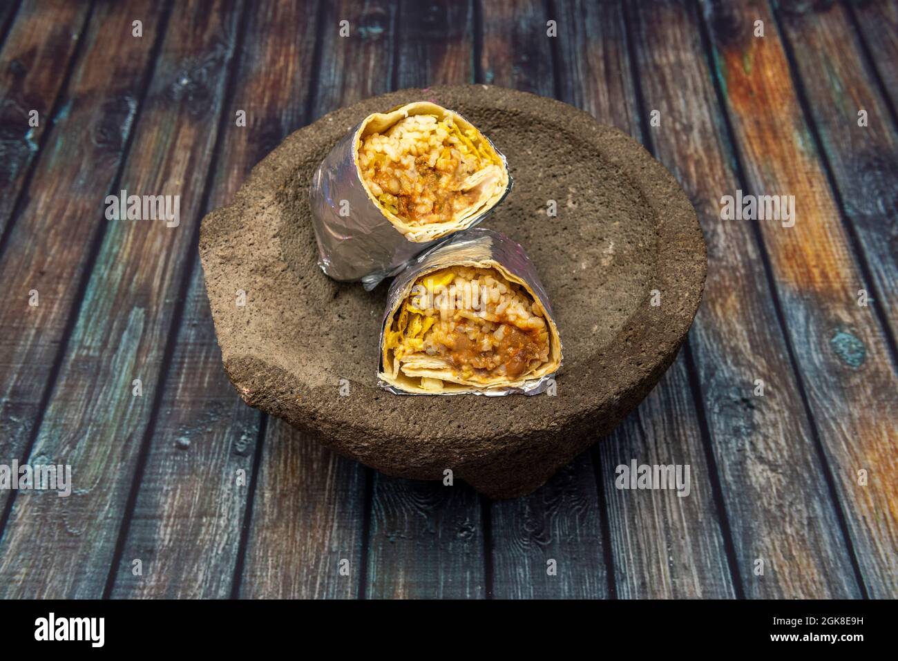Mexican chili con carne burrito wrapped in aluminum foil on volcanic ...