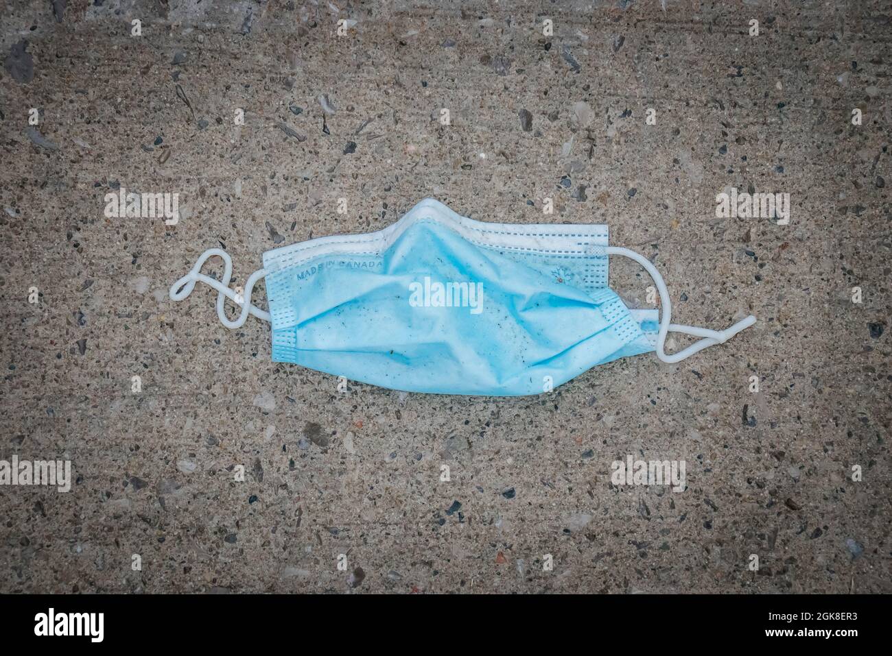 A dirty disposable face mask left as rubbish on the ground Stock Photo ...