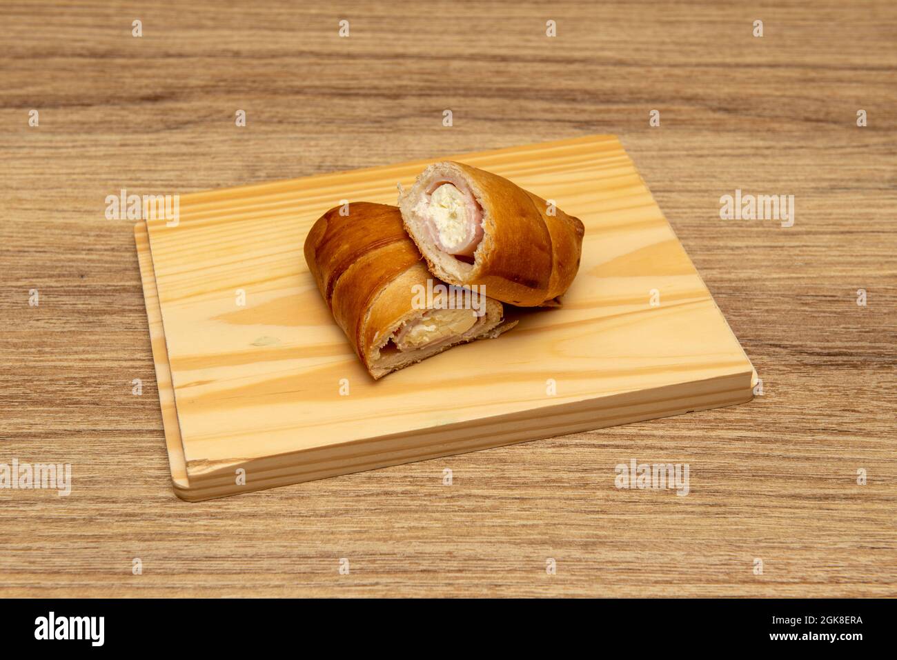 Venezuelan cachito stuffed with ham and cream cheese on pine wood board ...