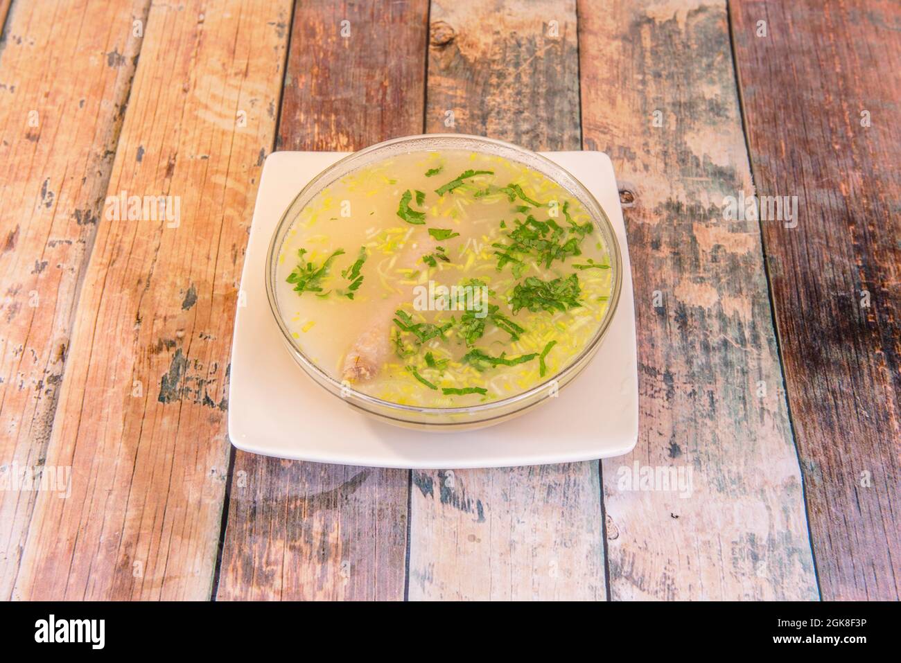 Glass bowl containing Peruvian recipe for boiled hen broth with chopped ...