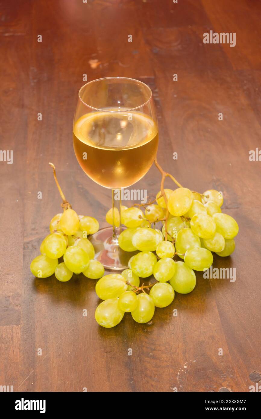 Closeup of the juicy green grapes with a glass of white wine on the ...