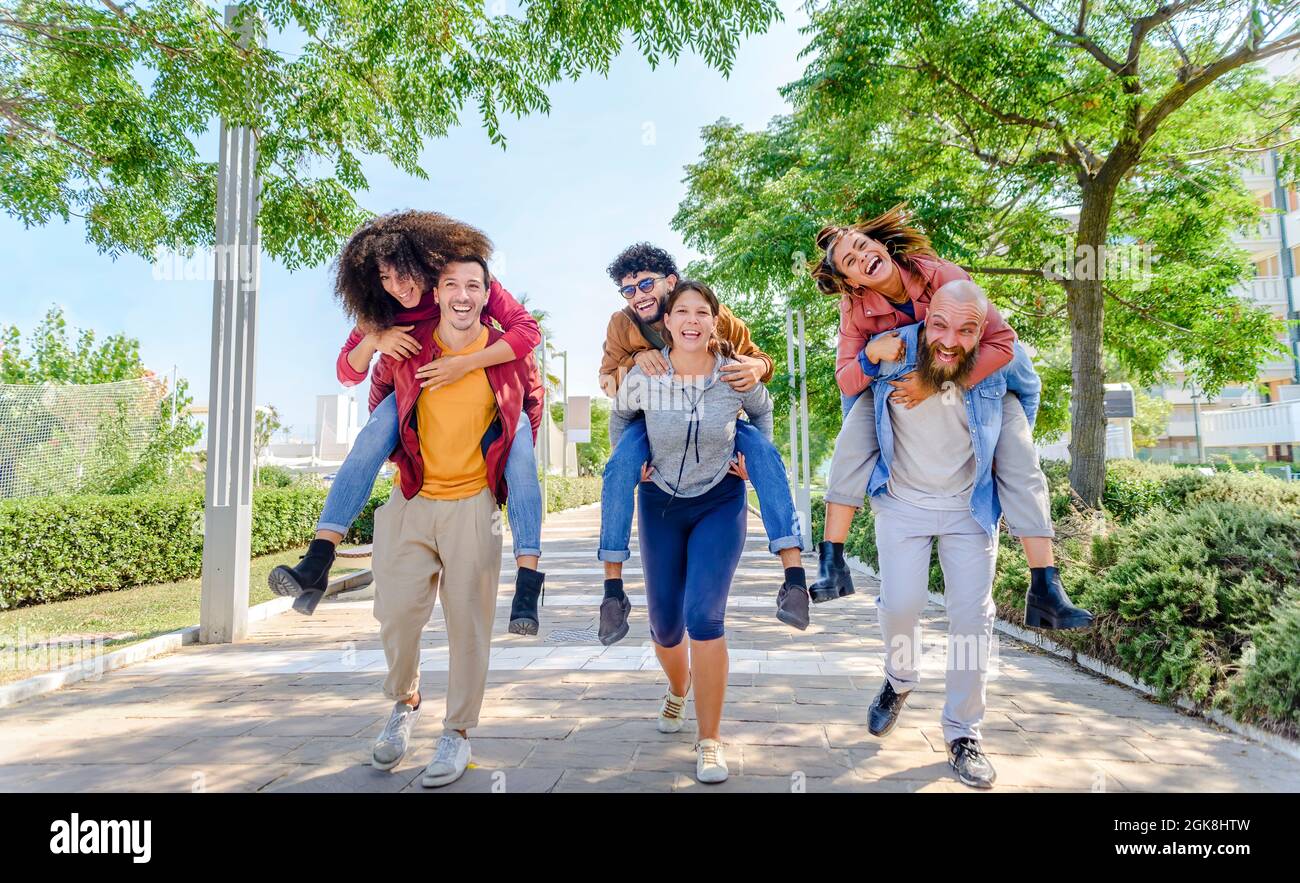 multiethnic group of friends running in the street outdoors laughing ...