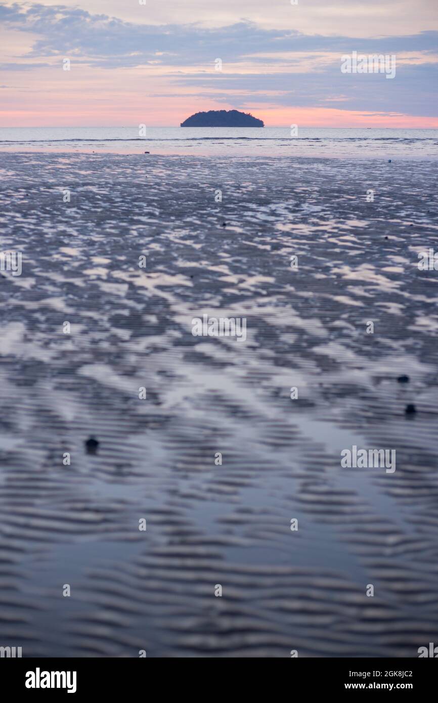 Sandy shore washed by shallow water of sea with hill on horizon under ...