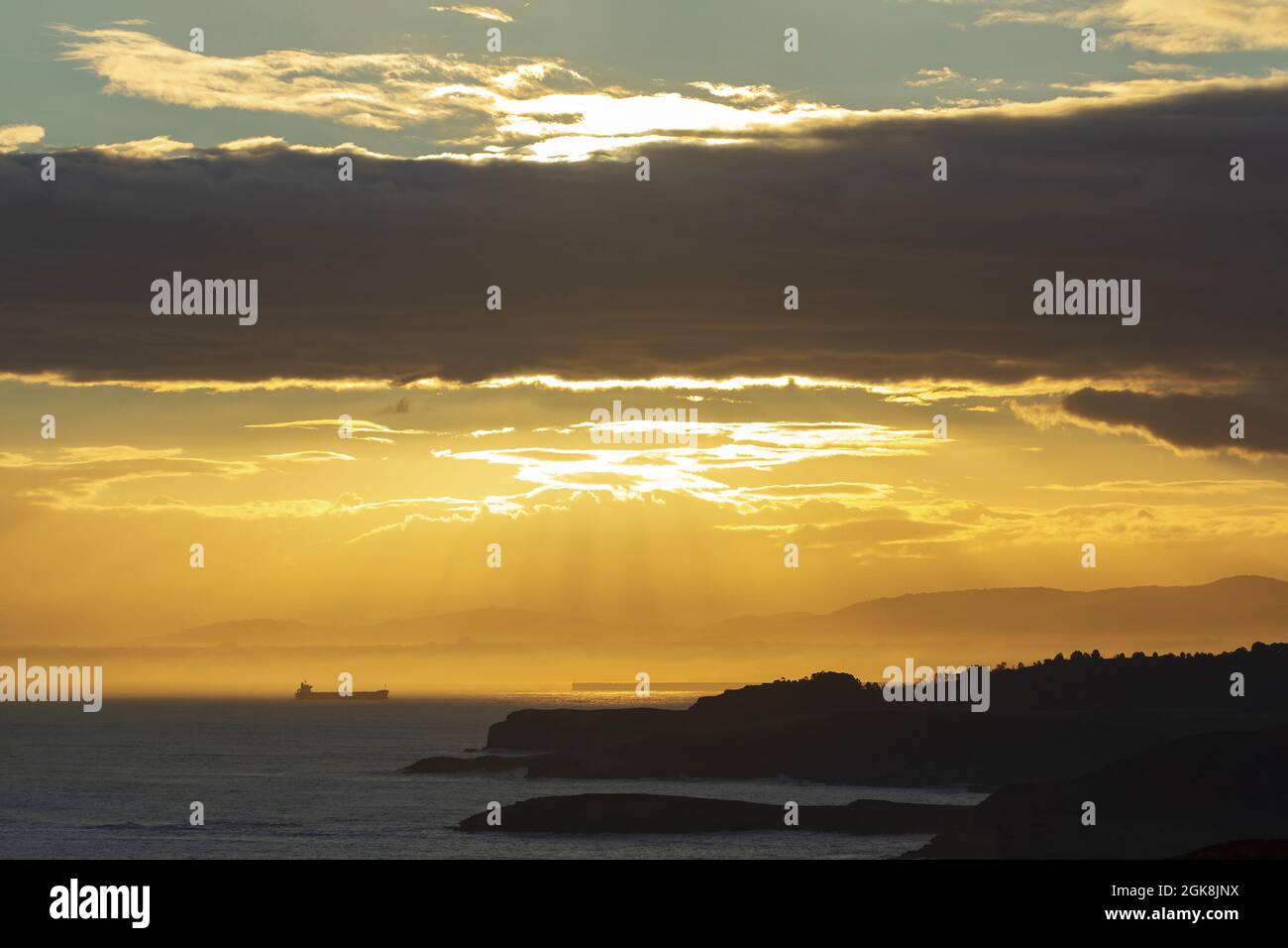 Picturesque scenery of hilly seacoast and sundown sky with sun rays ...