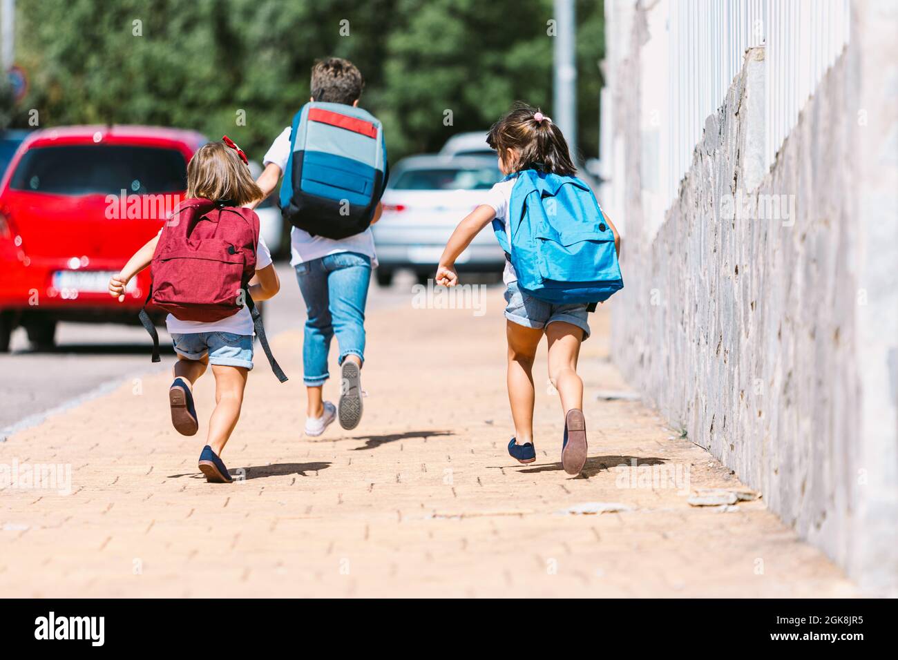 Back view of anonymous schoolkids with backpacks running on tiled ...