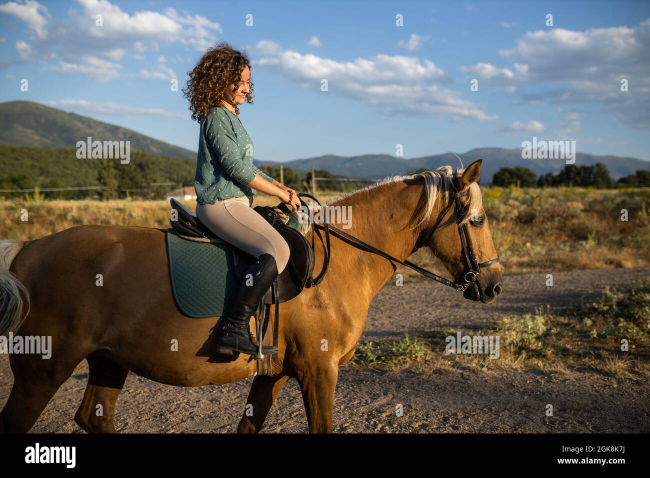 Side view of female riding stallion with smooth brown coat on rough ...