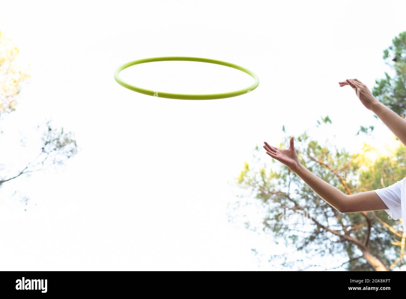 Low angle of crop anonymous person throwing hula hoop into air while ...