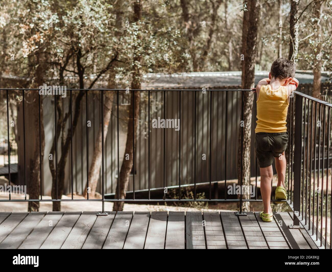 Back view of unrecognizable little boy standing on veranda of modern ...