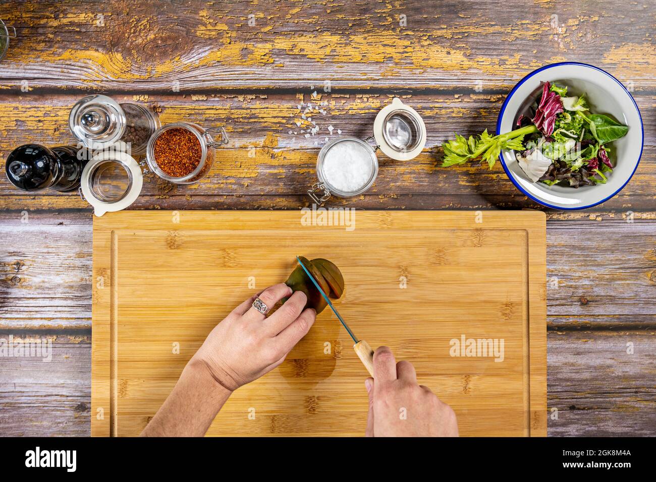 Top view image of female chef's hands with ring cutting a tomato on a ...