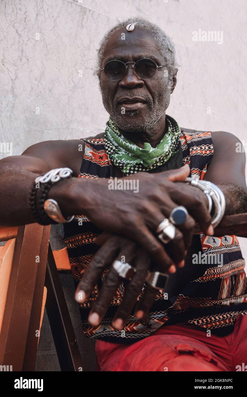 Full body side view of senior male sitting at RV car parked on grassy ...