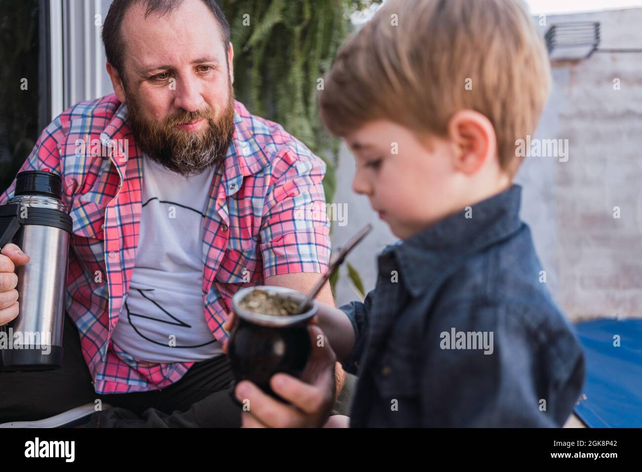 Sincere child with calabash gourd of infused drink against cheerful ...