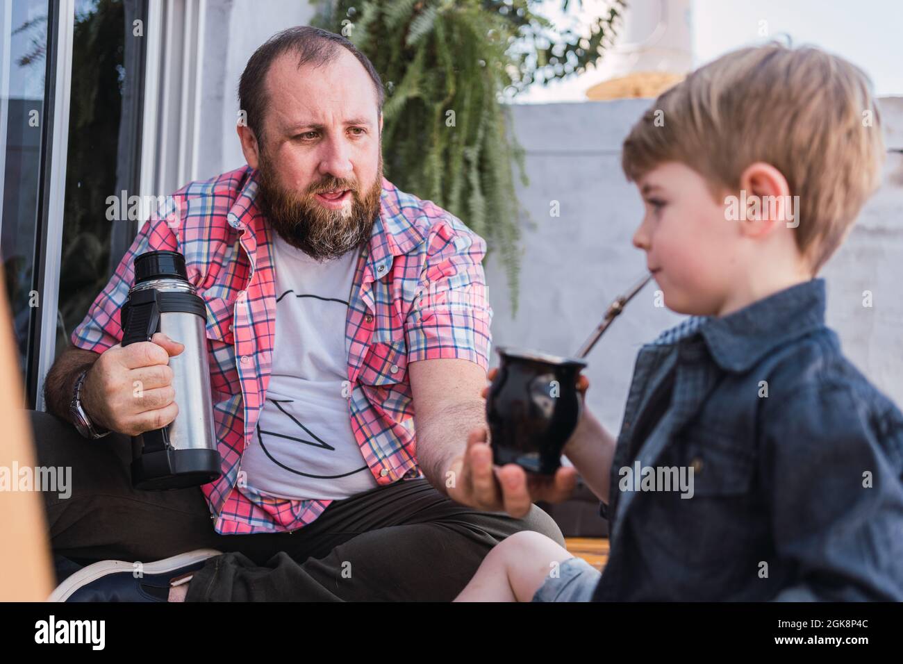 Sincere child with calabash gourd of infused drink against cheerful ...