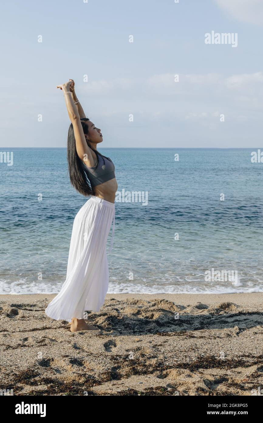 Side view of young ethnic female cracking knuckles during yoga practice ...