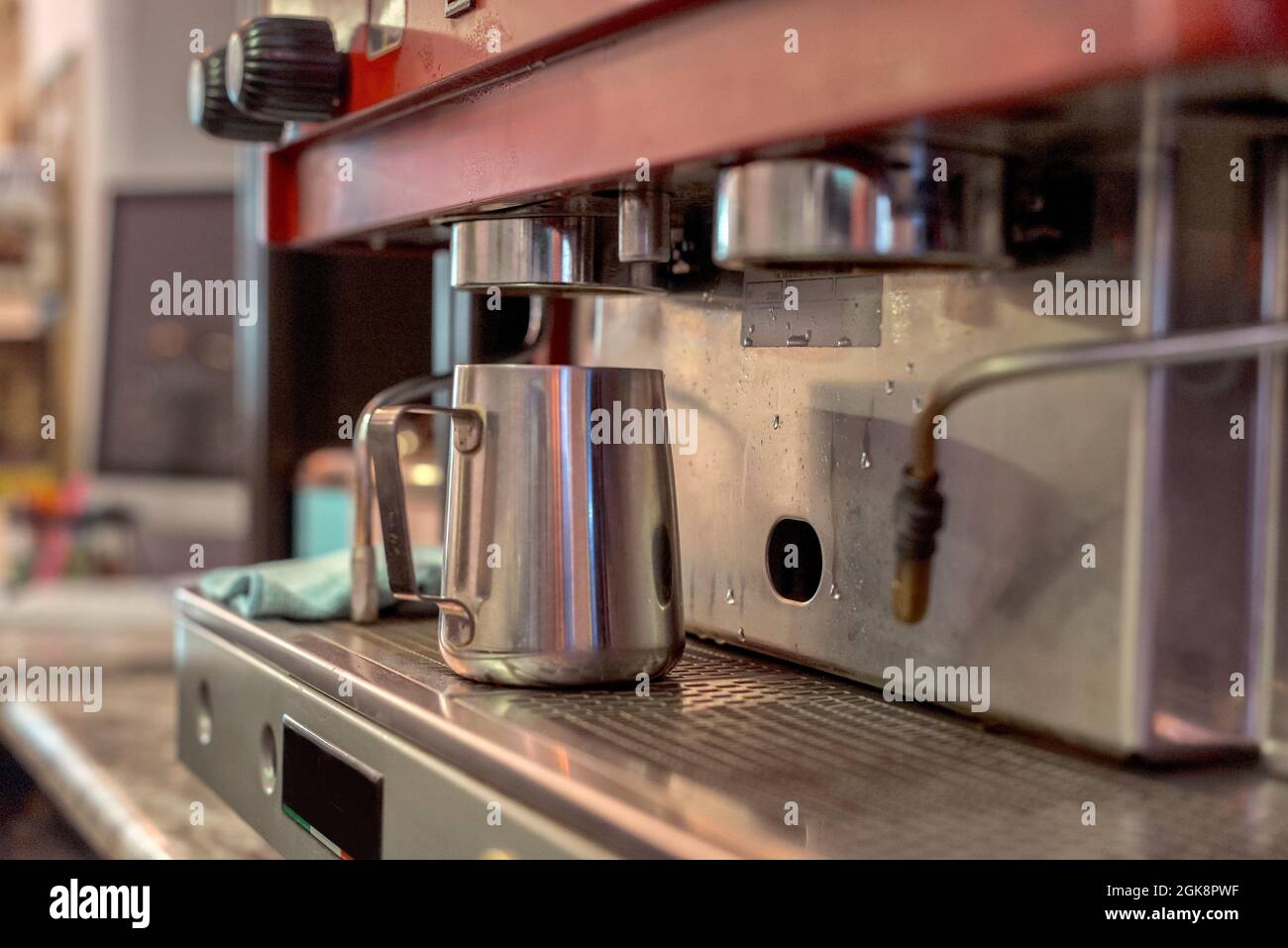 Metal pitcher on rack of professional coffee maker on table in ...