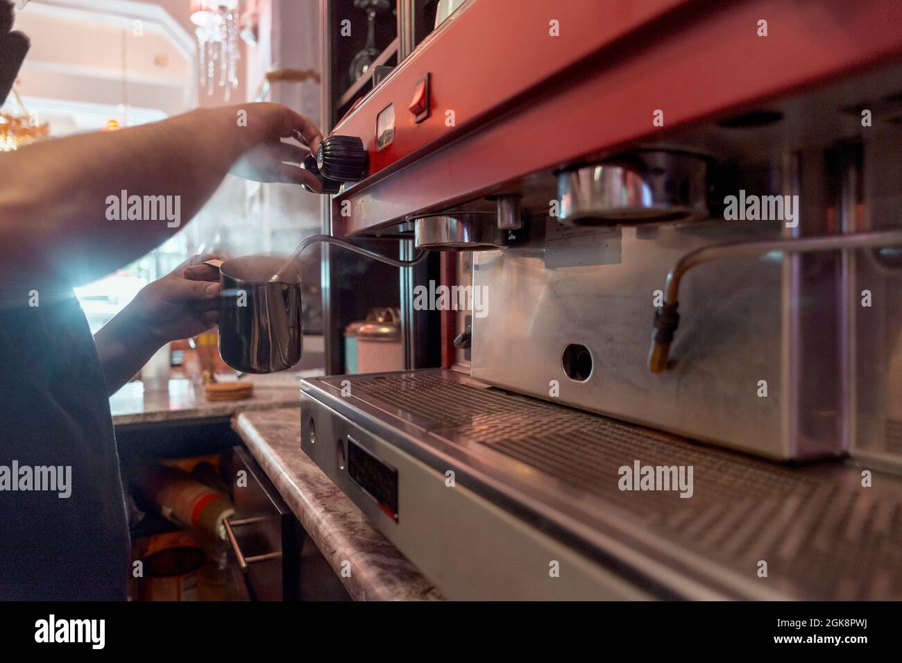 Crop anonymous cafeteria employee against professional coffee maker ...