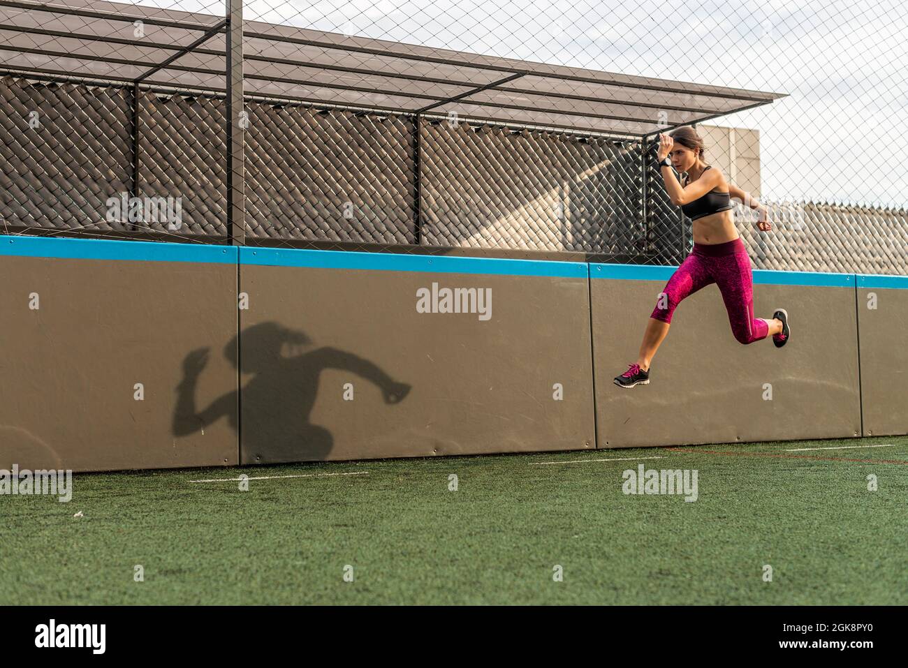 Full body of enduring female athlete in activewear jumping above ground ...