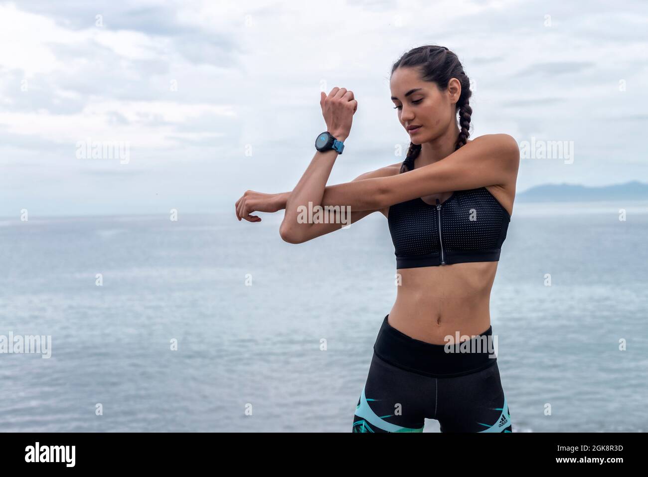 Slim female runner in activewear stretching arms and warming up body ...