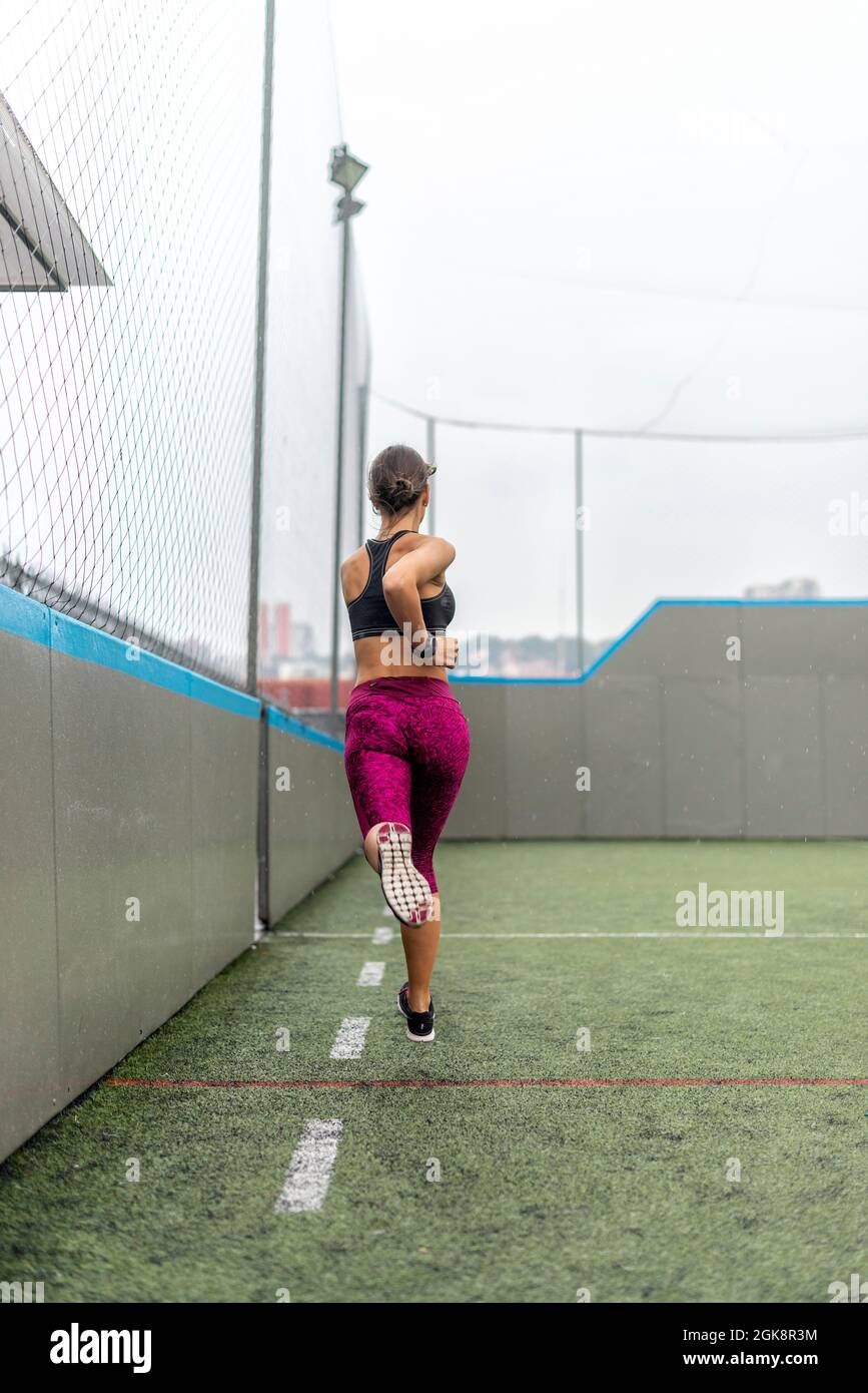 Full body of enduring female athlete in activewear running above ground ...