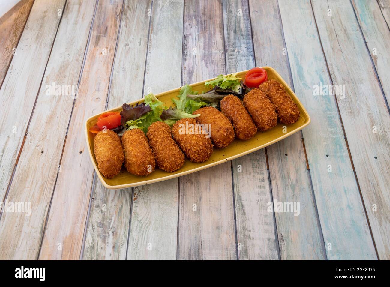 Tapa of homemade Iberian ham croquettes with a little salad on a ...