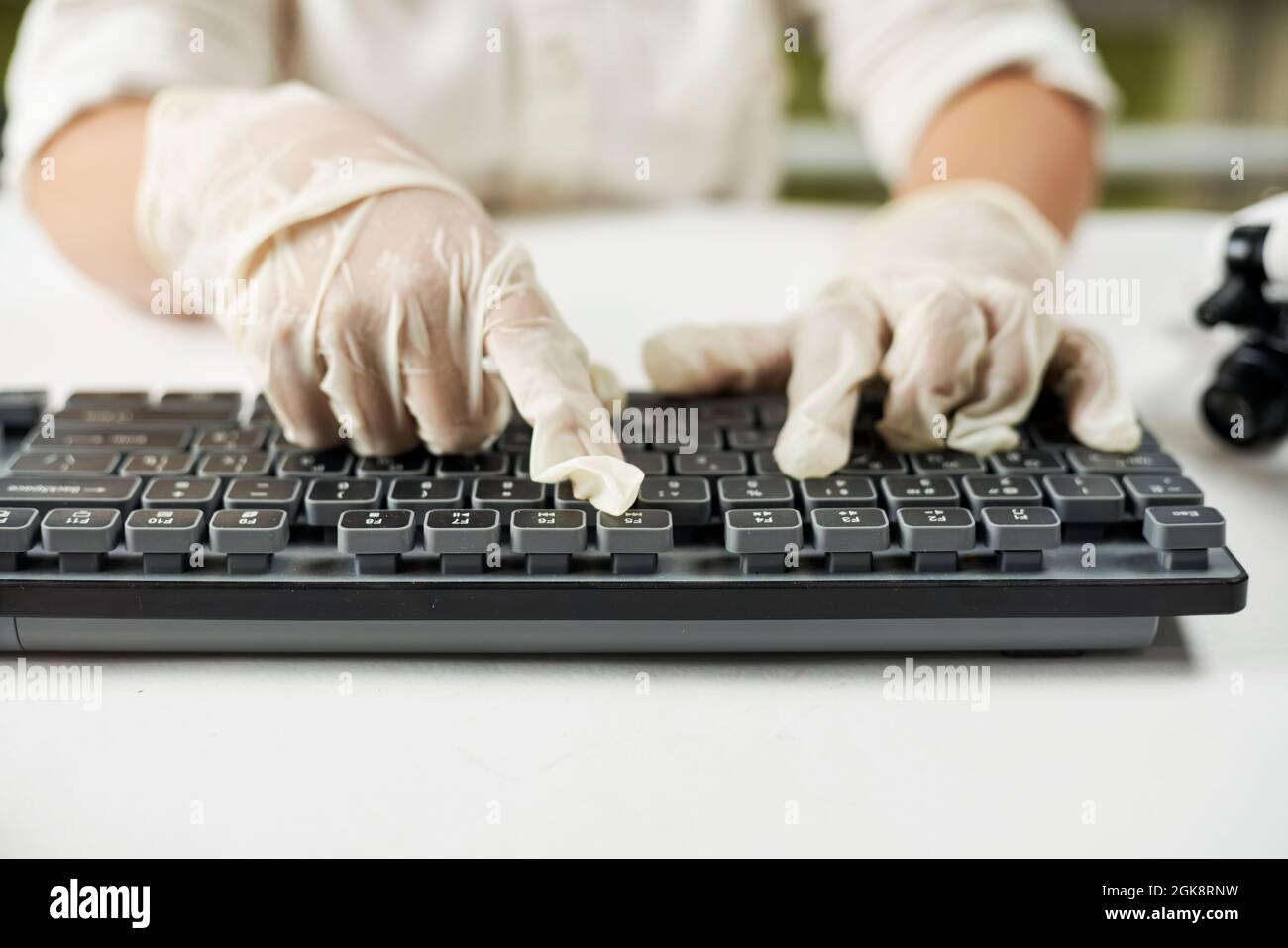 Close up shot of hands of a young child in protective gloves typing on ...