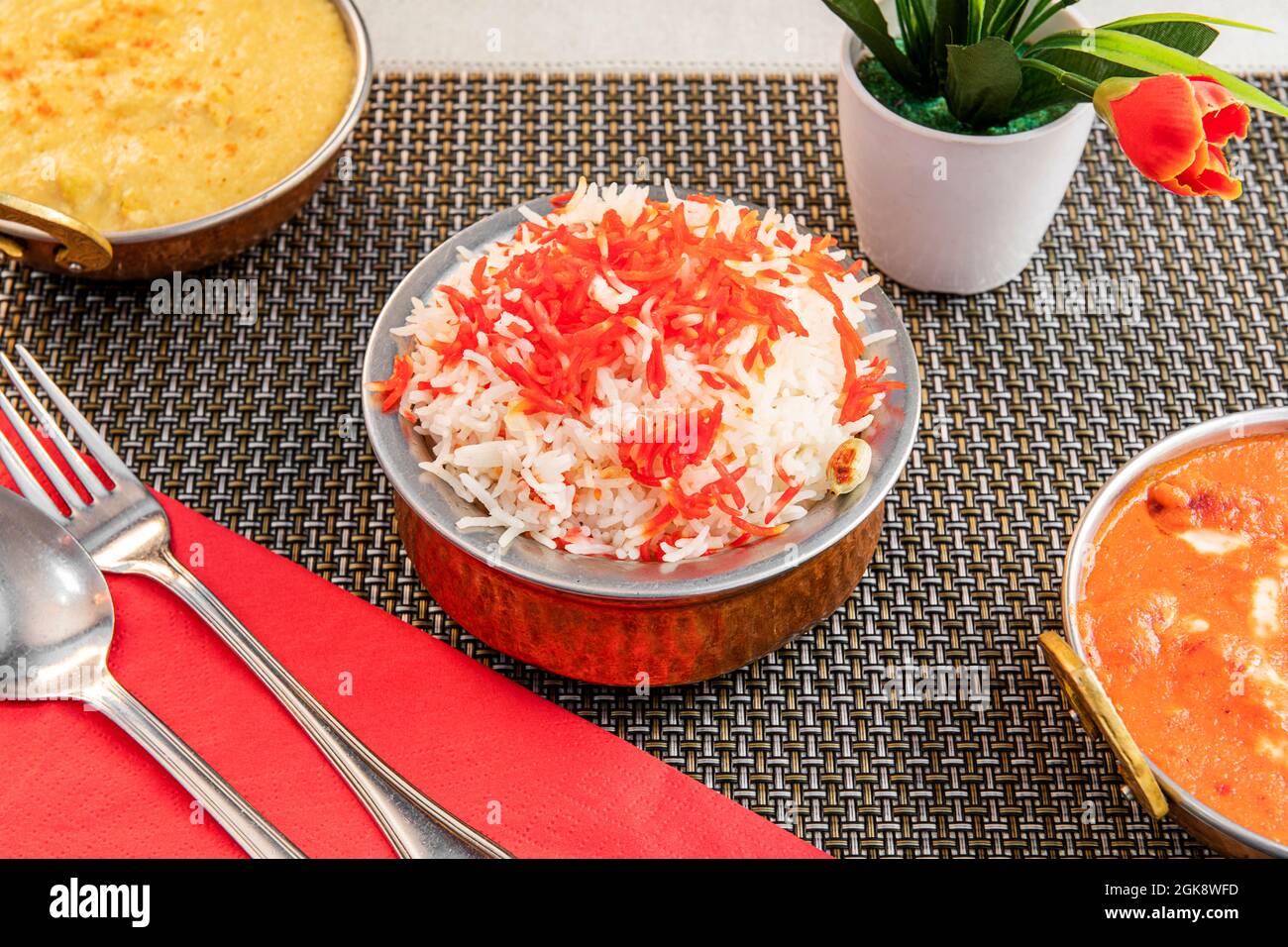 Typical Pakistani restaurant metal bowl with pilau rice on gray trivet ...