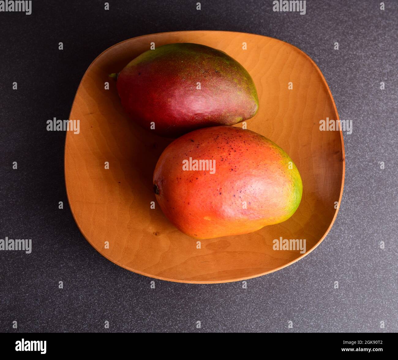 two colourful mangoes an a wooden plate Stock Photo - Alamy