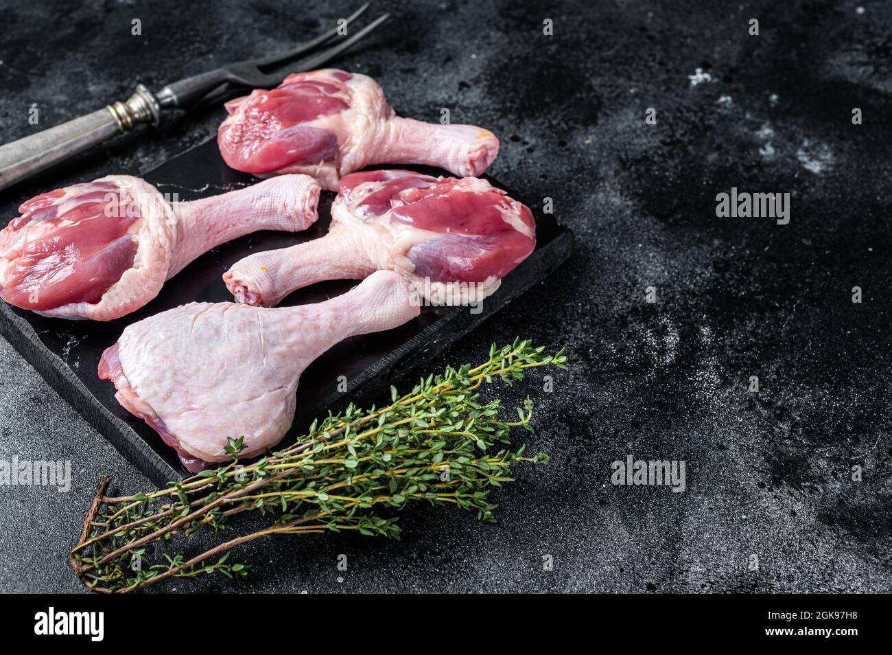 Uncooked Raw Duck legs drumsticks on marble board. Black background ...